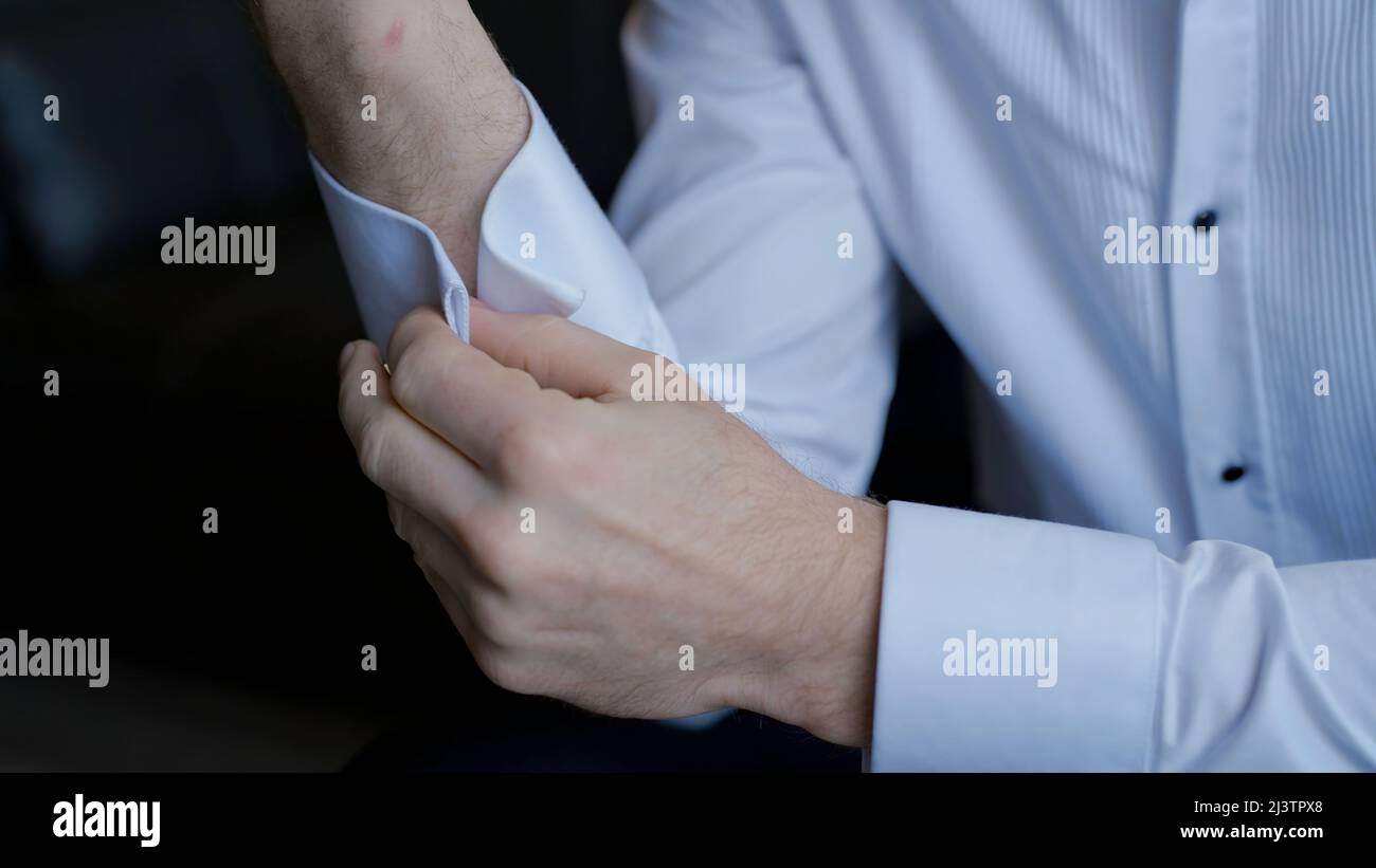 The man gets dressed and does his buttons on the sleeves of his white ...