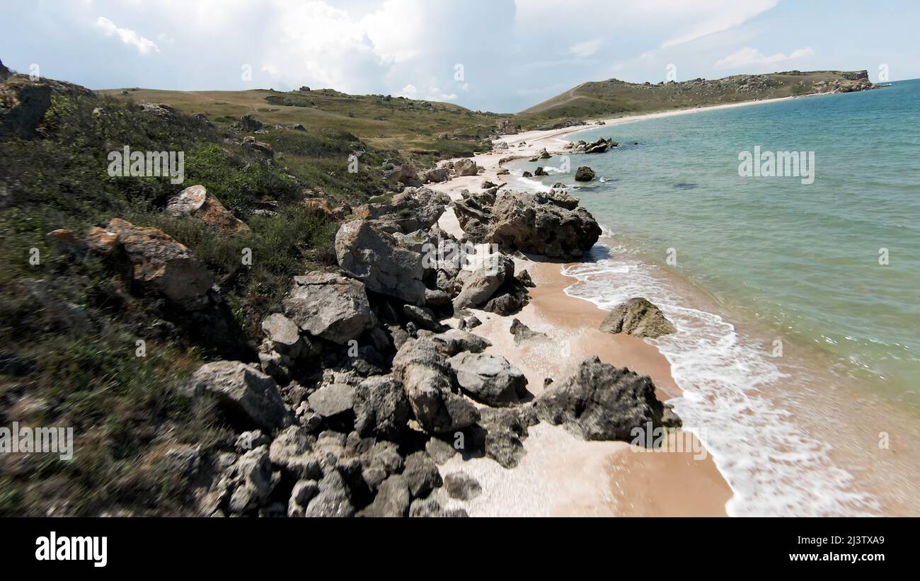 Flying above beautiful rocky sea shore with green meadow. Action ...