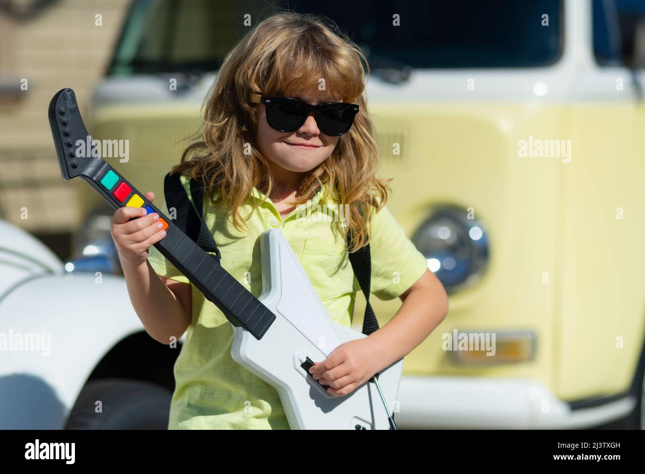 Cute child boy sings and plays on the electric guitar with fun emotions ...