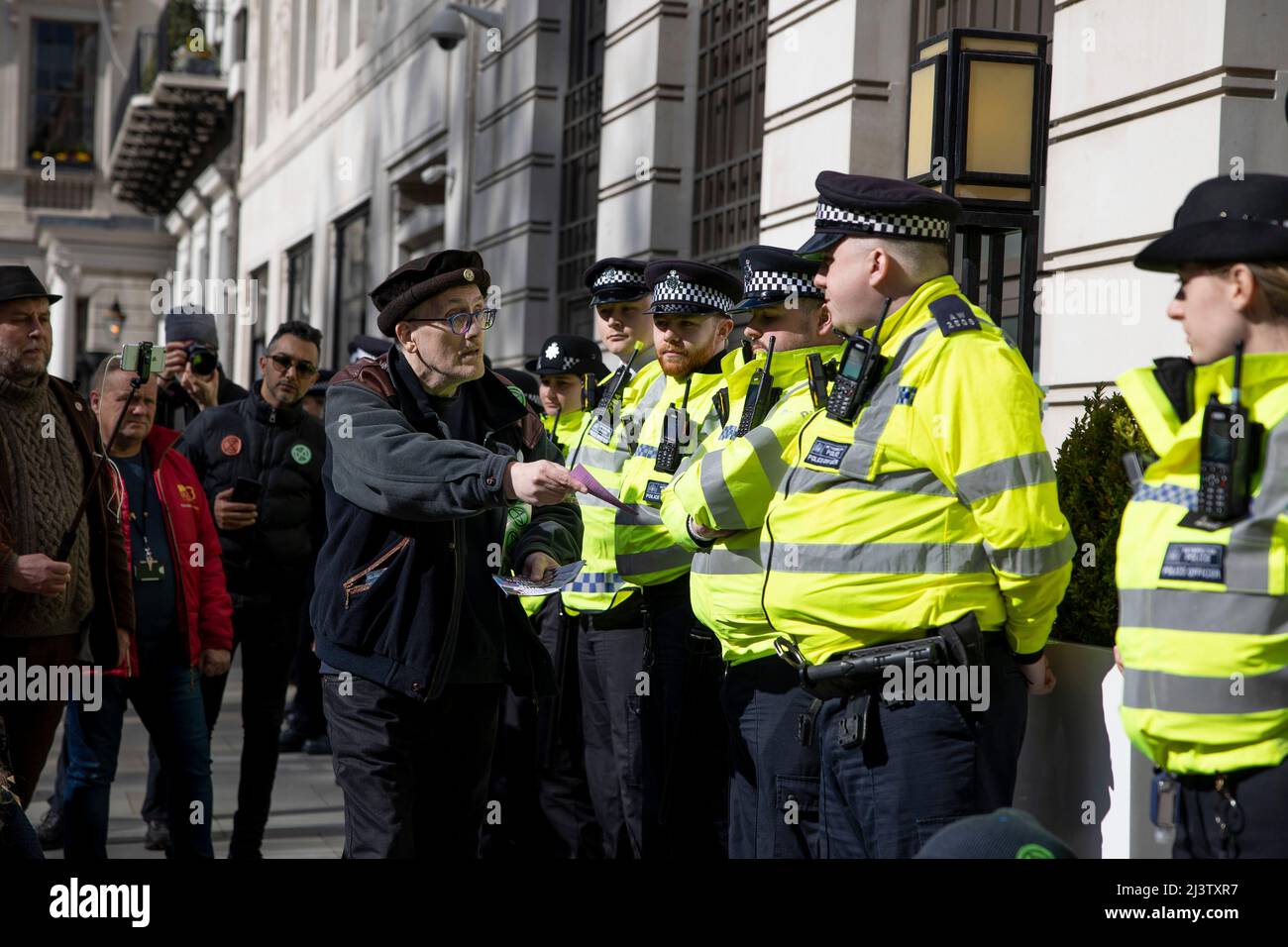 A protester is seen handing leaflet to the Met police in front of the ...