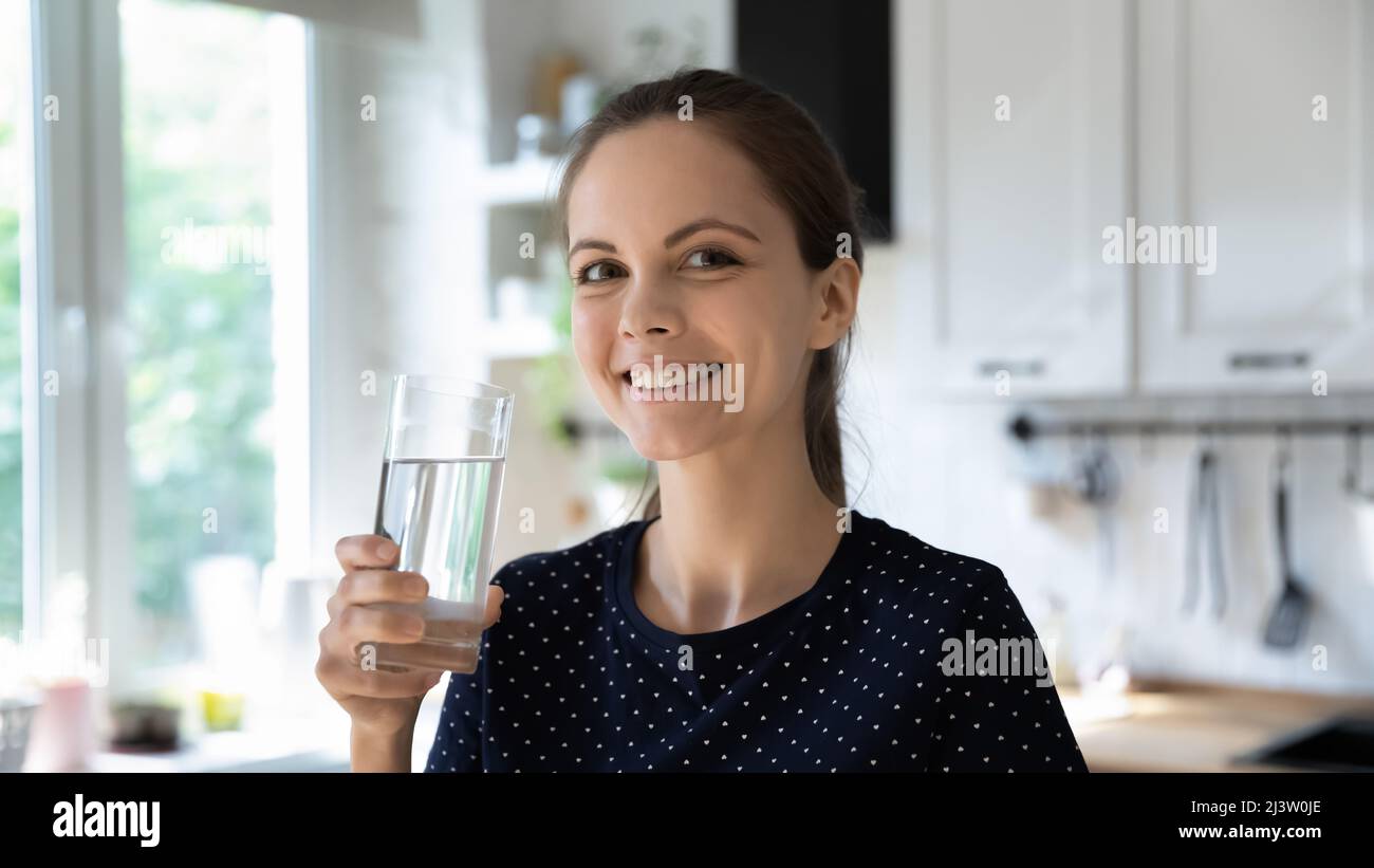 Woman holds glass of water, smiles looks at camera Stock Photo - Alamy