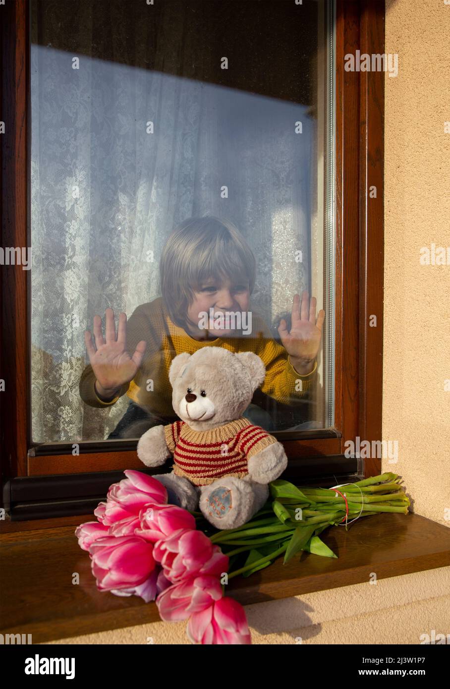 child, a boy, hiding outside the window, in front of him on the ...
