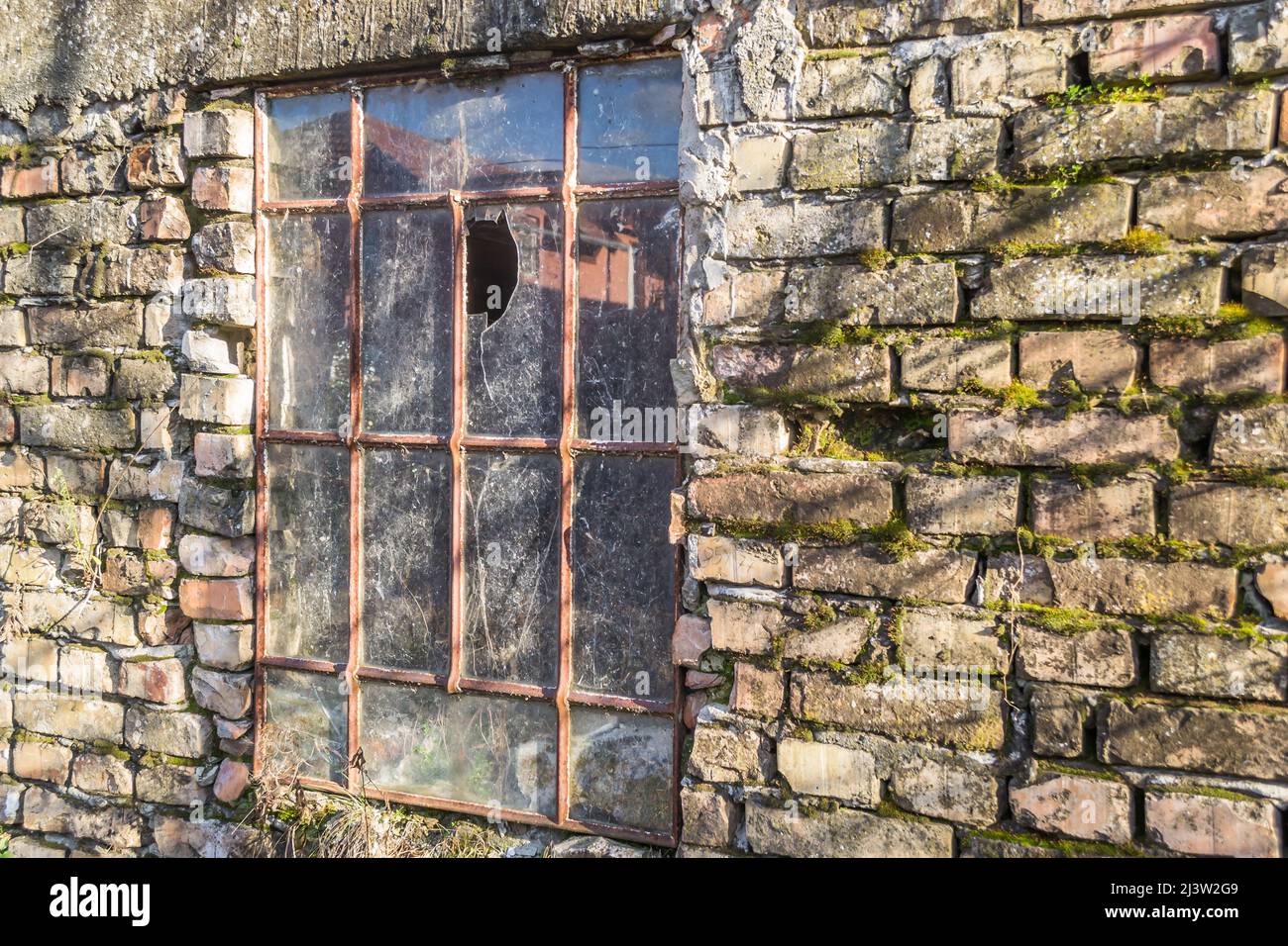 An old metal window with broken glass, on the wall of an old ...