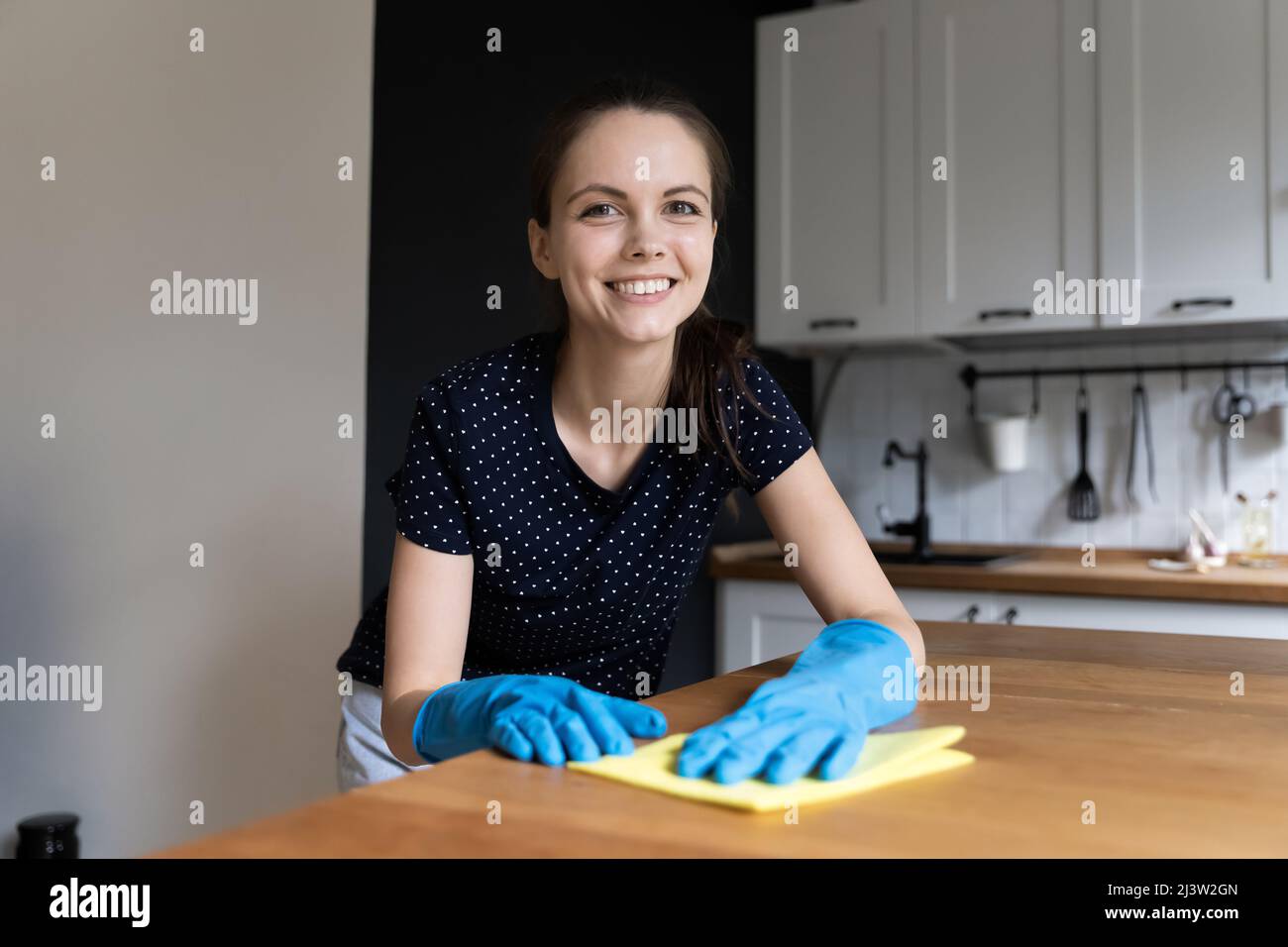 Woman wear gloves cleaning kitchen counter smile look at camera Stock ...