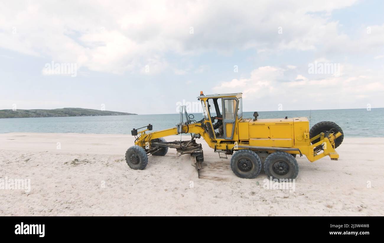 Top view of tractor on beach. Action. Bulldozer clears white beach by ...