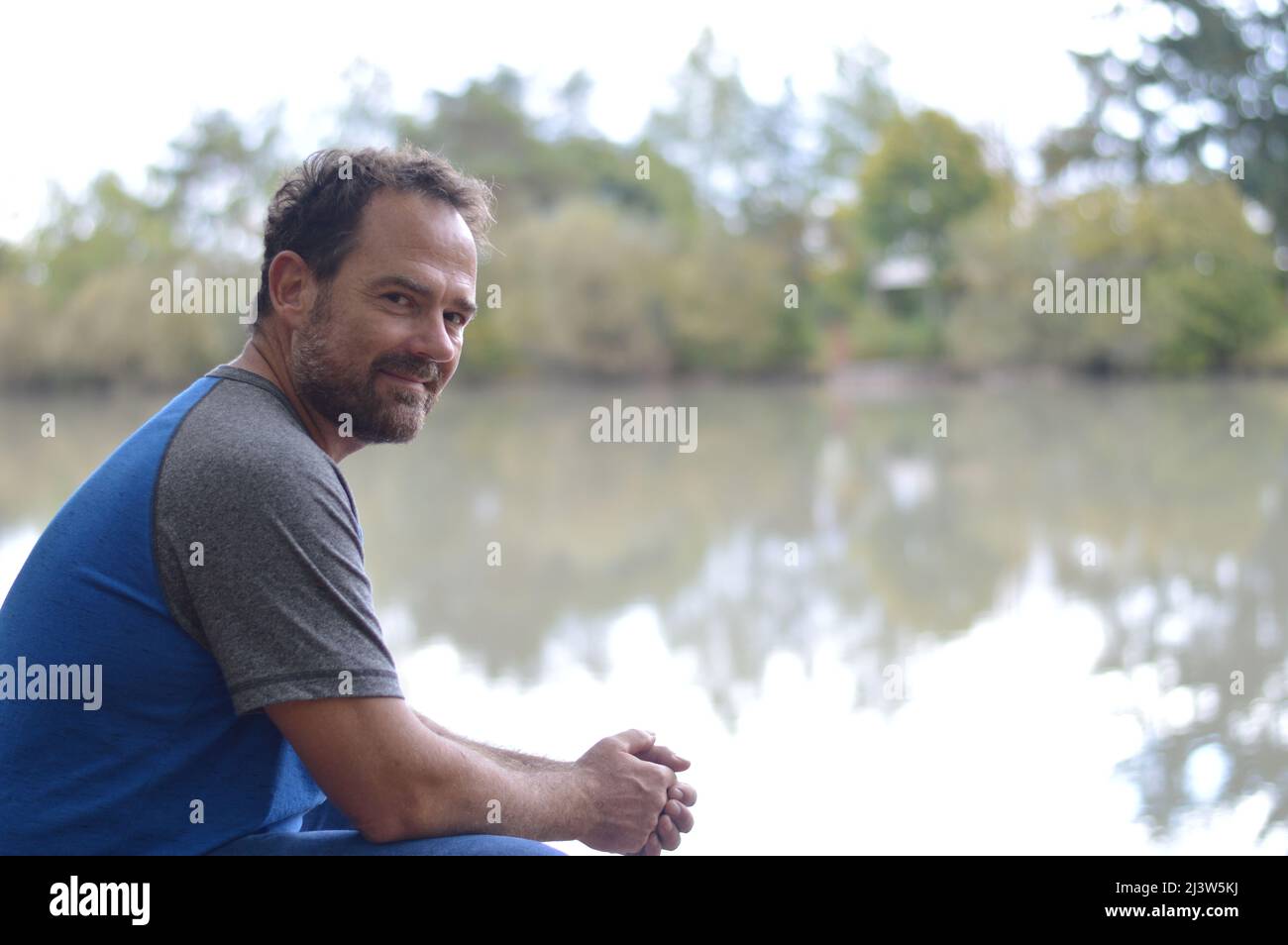 a man squatting by a lake shore Stock Photo - Alamy