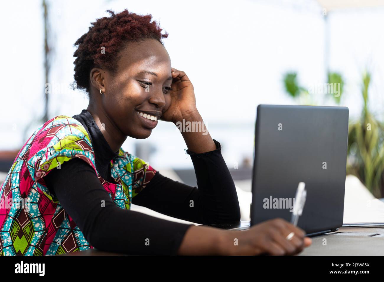 Cheerful young African woman following a tutorial from her favorite ...