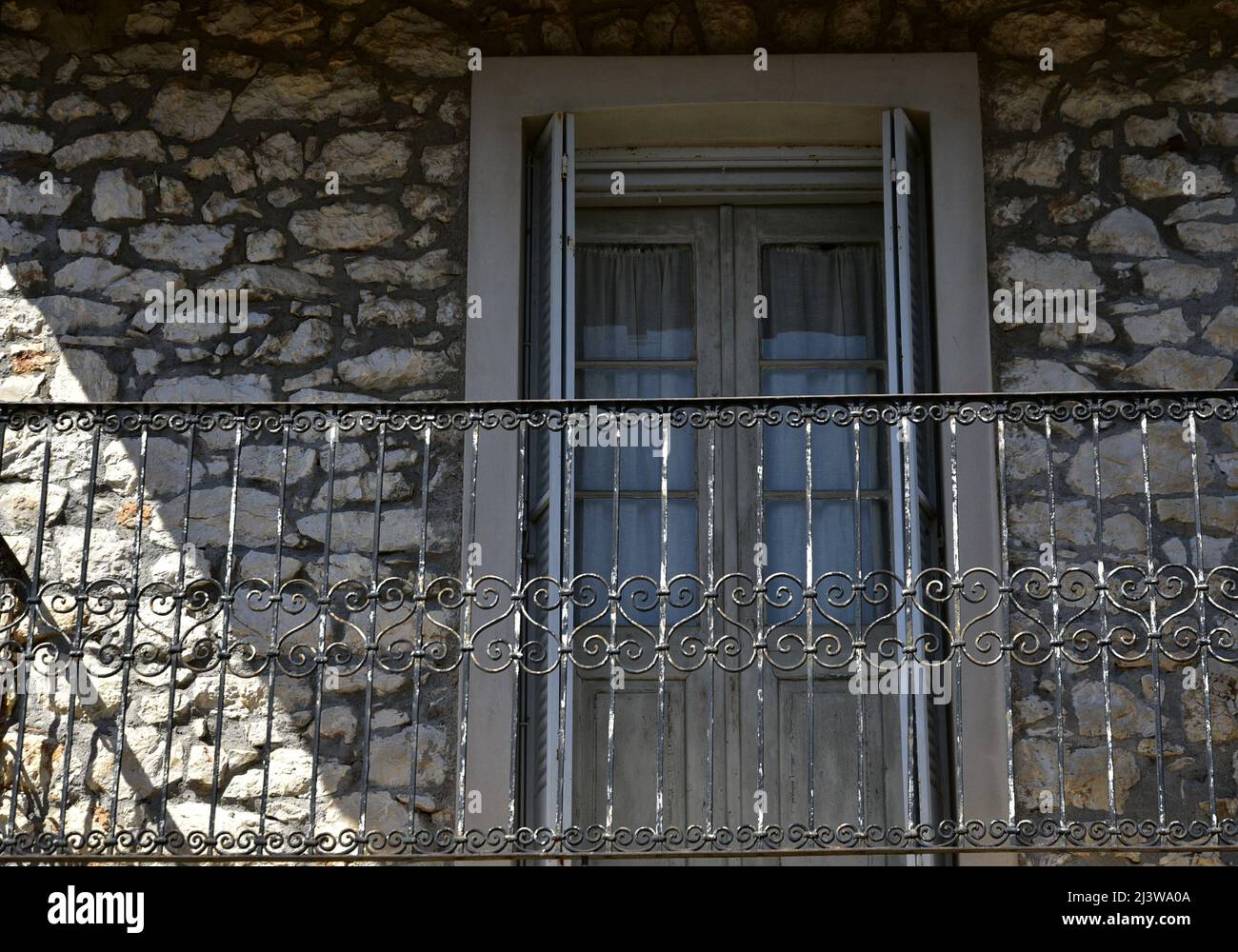 Old traditional rural house facade with a stone wall, wooden window and ...