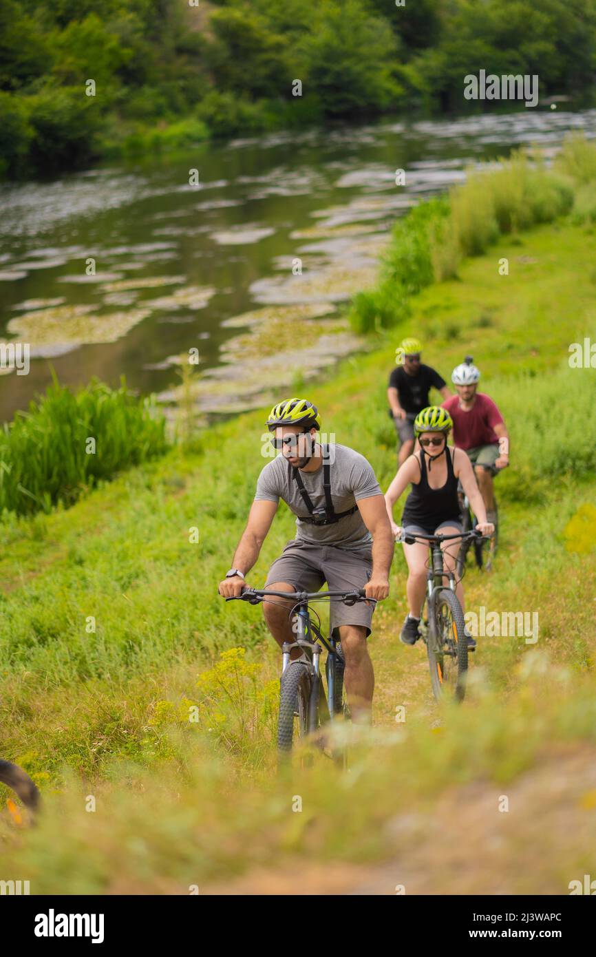 Handsome and fit guy is leading his friends while riding their bikes ...