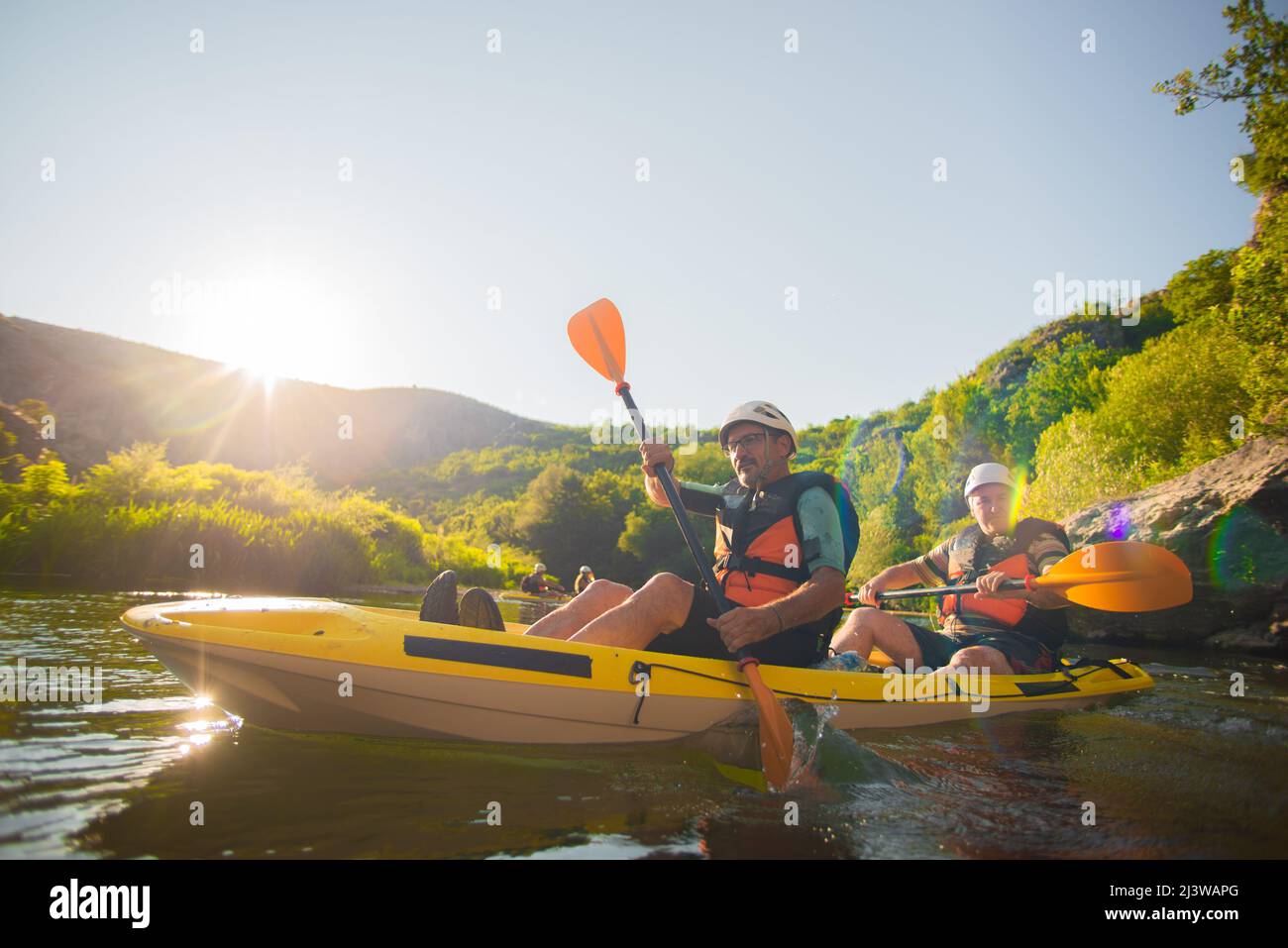 Two senior male friends are kayaking together while trying to get back ...