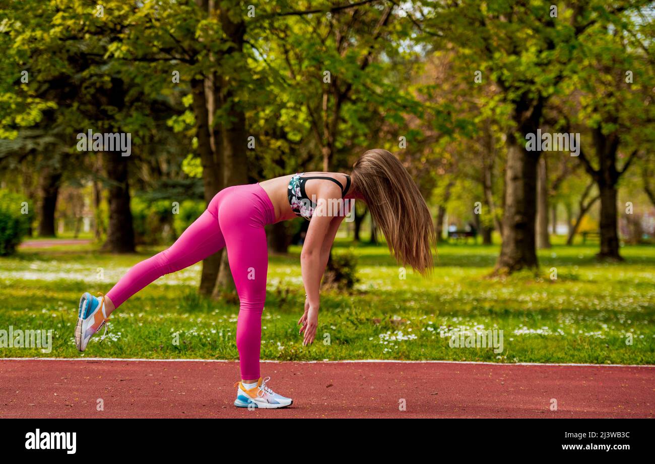 Young attractive toned brunette woman working out outside in a park in ...