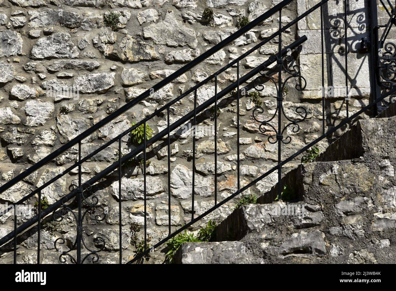 Old traditional handcrafted stone wall and a stairway with a wrought ...