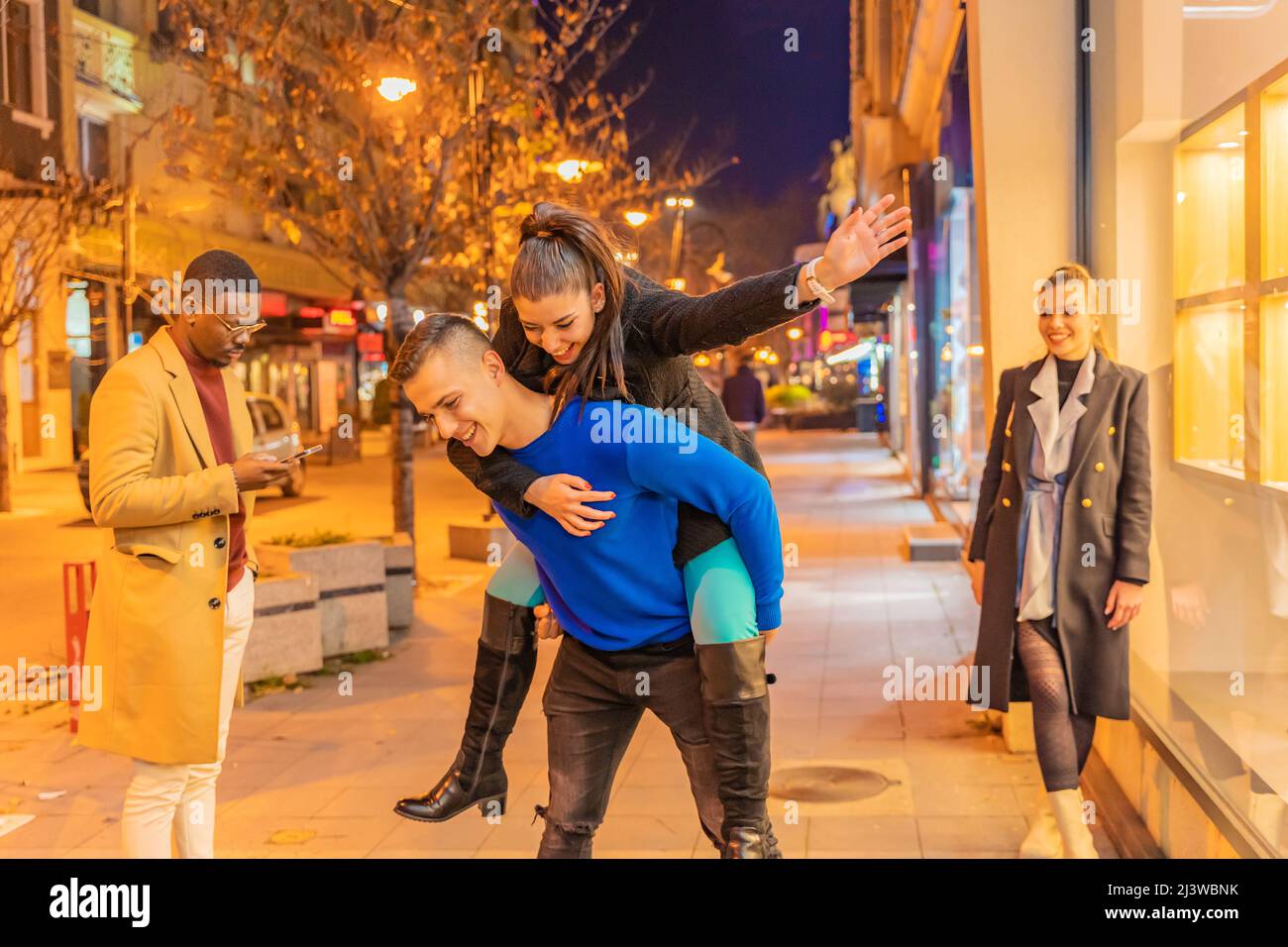 Attractive and beautiful girl is doing a piggyback ride on her boy ...