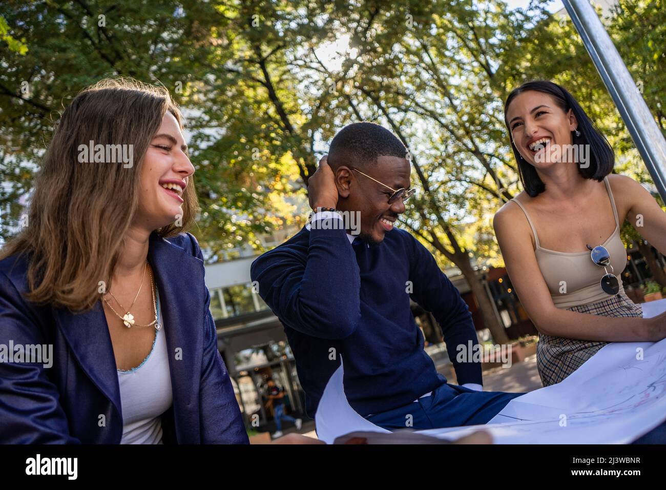 Three multiracial business people are laughing adn smiling while making ...