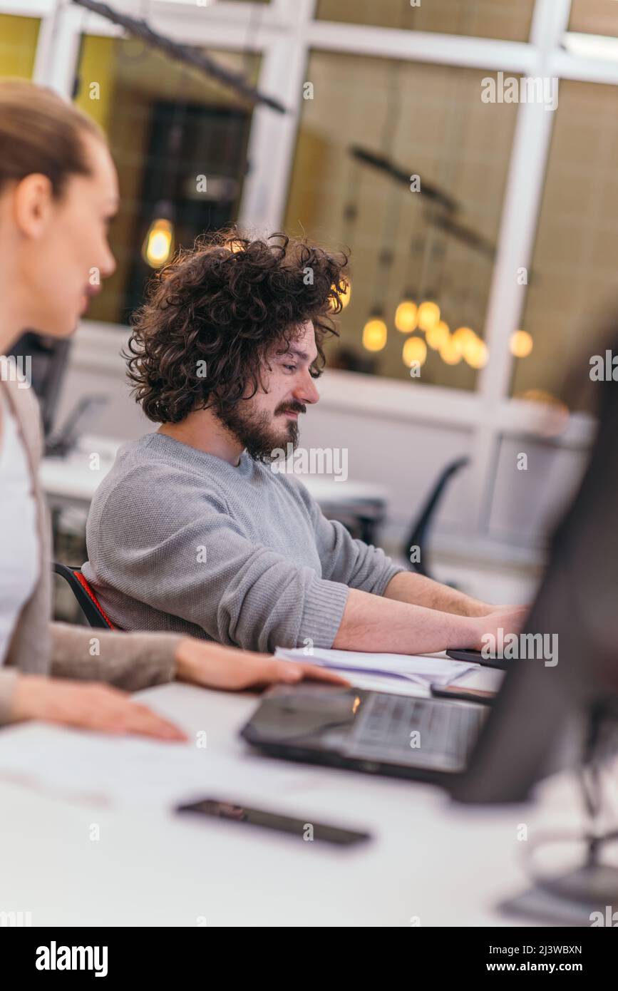 Two colleagues working on a project in modern startup offices. Guy with ...