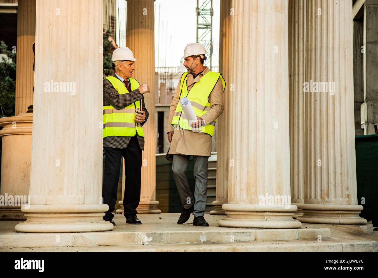 Two construction workers are standing and talking at the construction ...