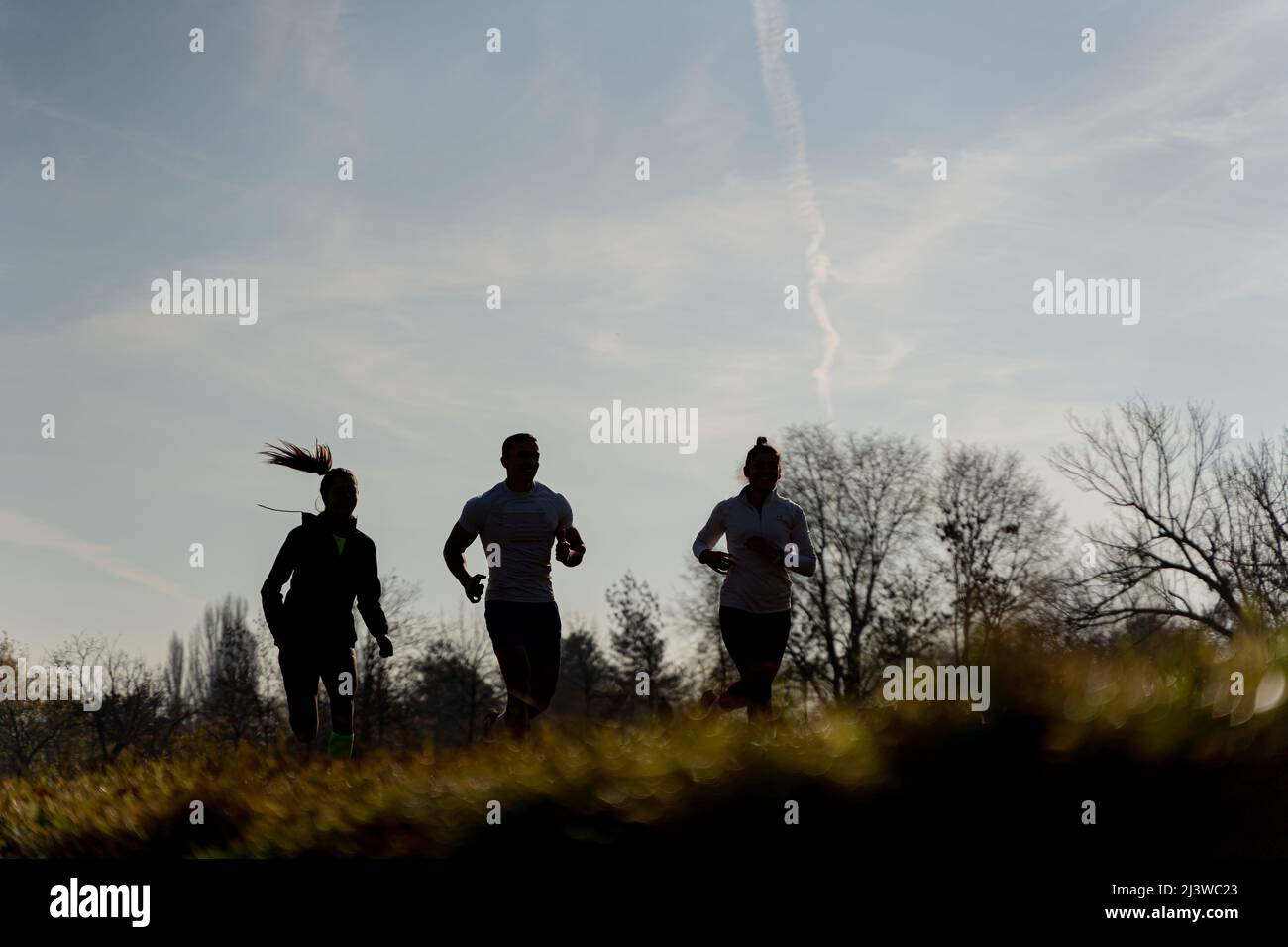 Silhouette of three amazing and fit runners, running together, low ...