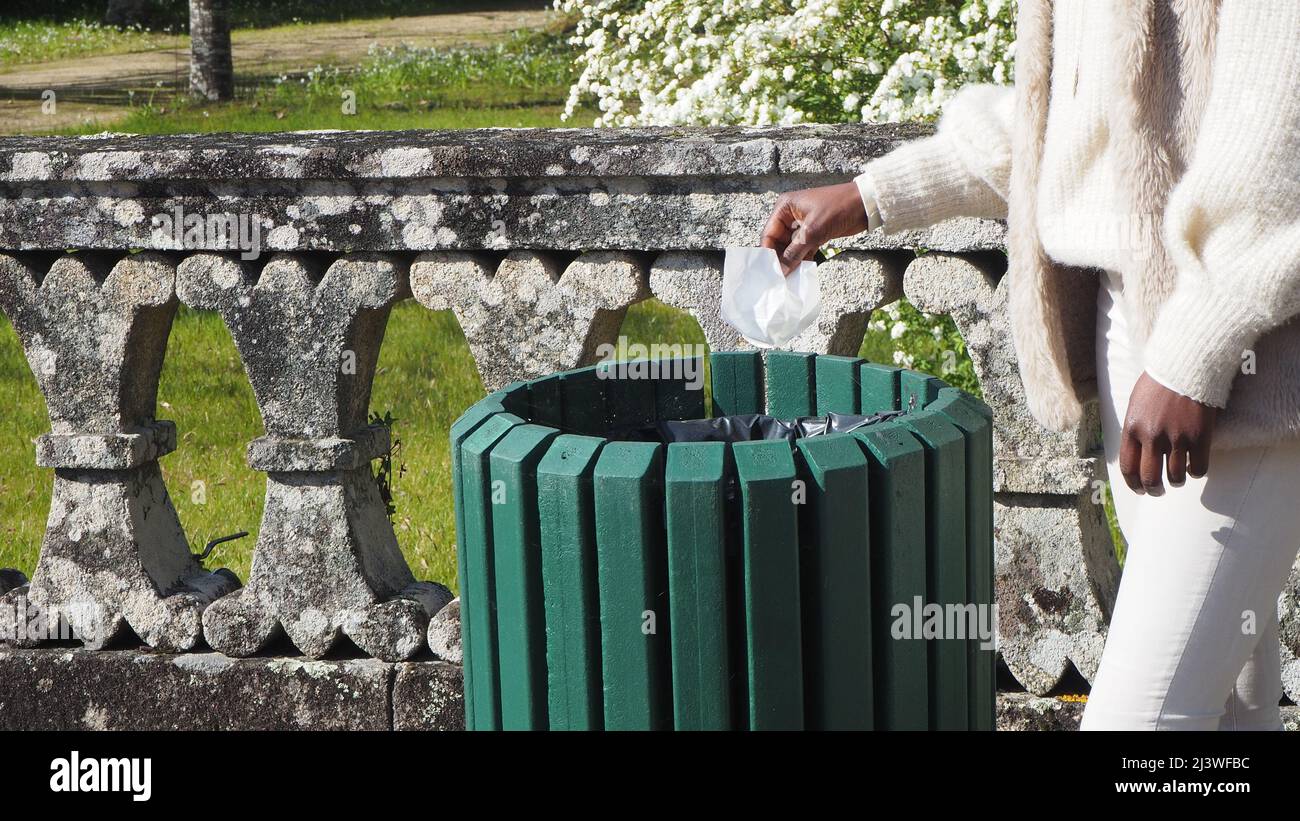 young woman throwing a tissue into a rubbish bin in a park Stock Photo ...