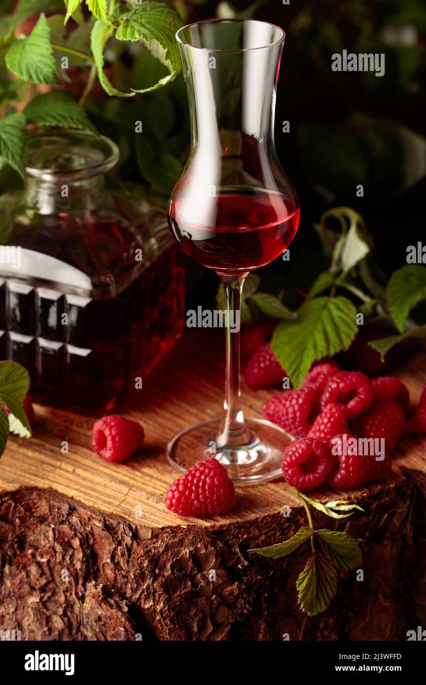 Raspberry liquor and fresh berries with leaves on a pine stump Stock ...