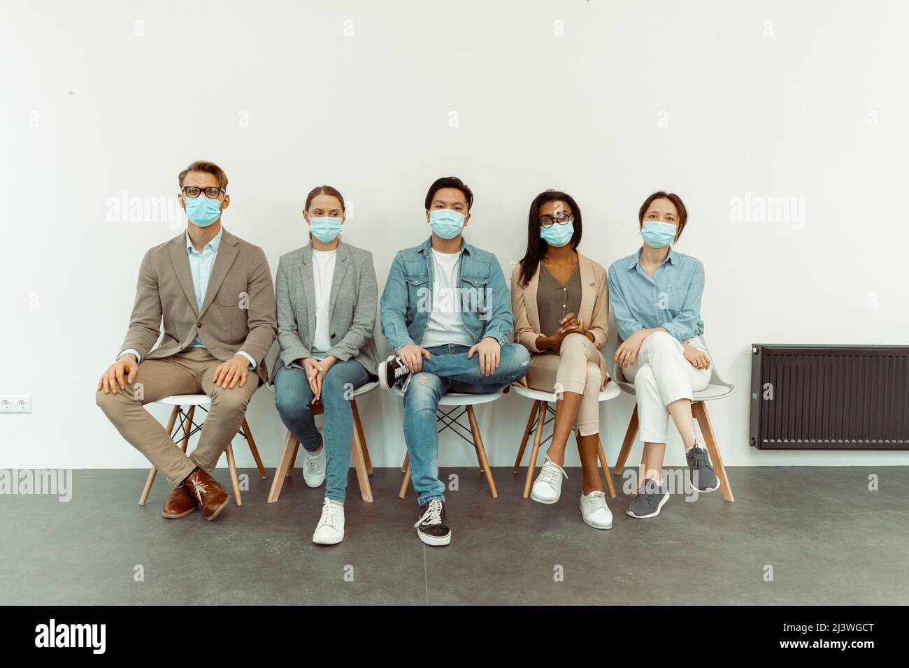 Colleagues in face masks sitting on chairs Stock Photo - Alamy