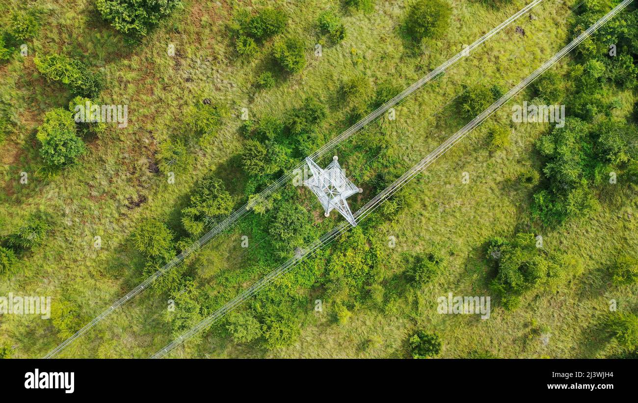 Aerial top down view high voltage steel power pylons in green field ...