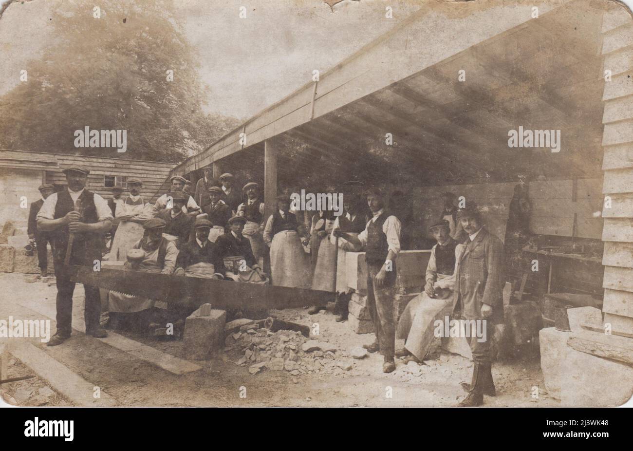 Photograph of stonemasons in a yard, early 20th century. Two men are ...