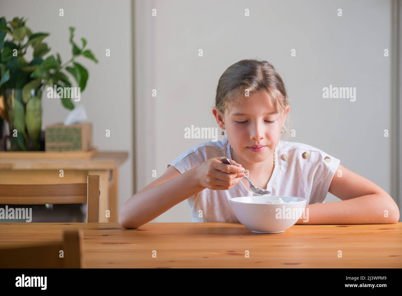 Blonde teenage girl eating cereal for breakfast. Lifestyle portrait ...