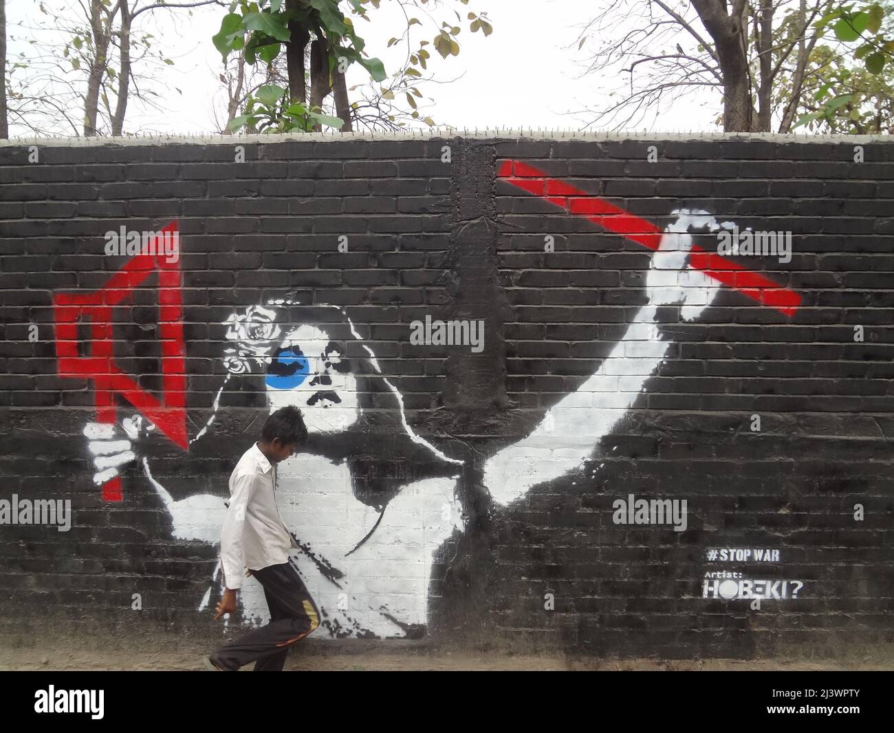 April 10, 2022, Dhaka, Bangladesh: A boy walks past a street graffiti ...