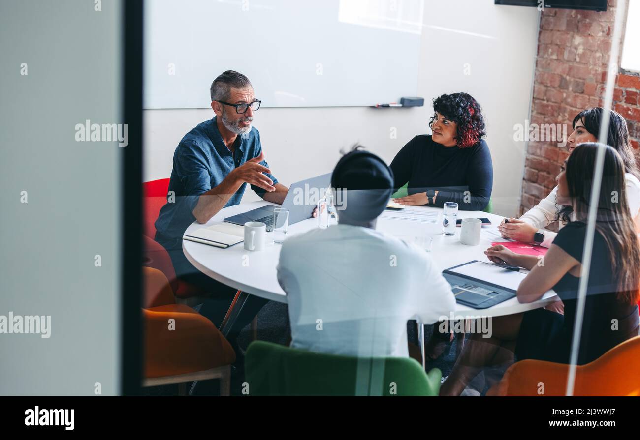 Experienced mature businessman briefing his colleagues in a meeting ...