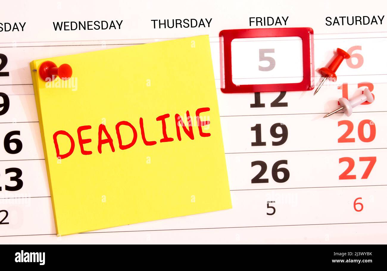 Deadline word written on a post note and hanged on the cork-board with ...