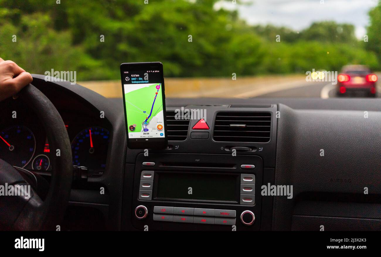 Driving and using waze maps application on smartphone on car dashboard ...