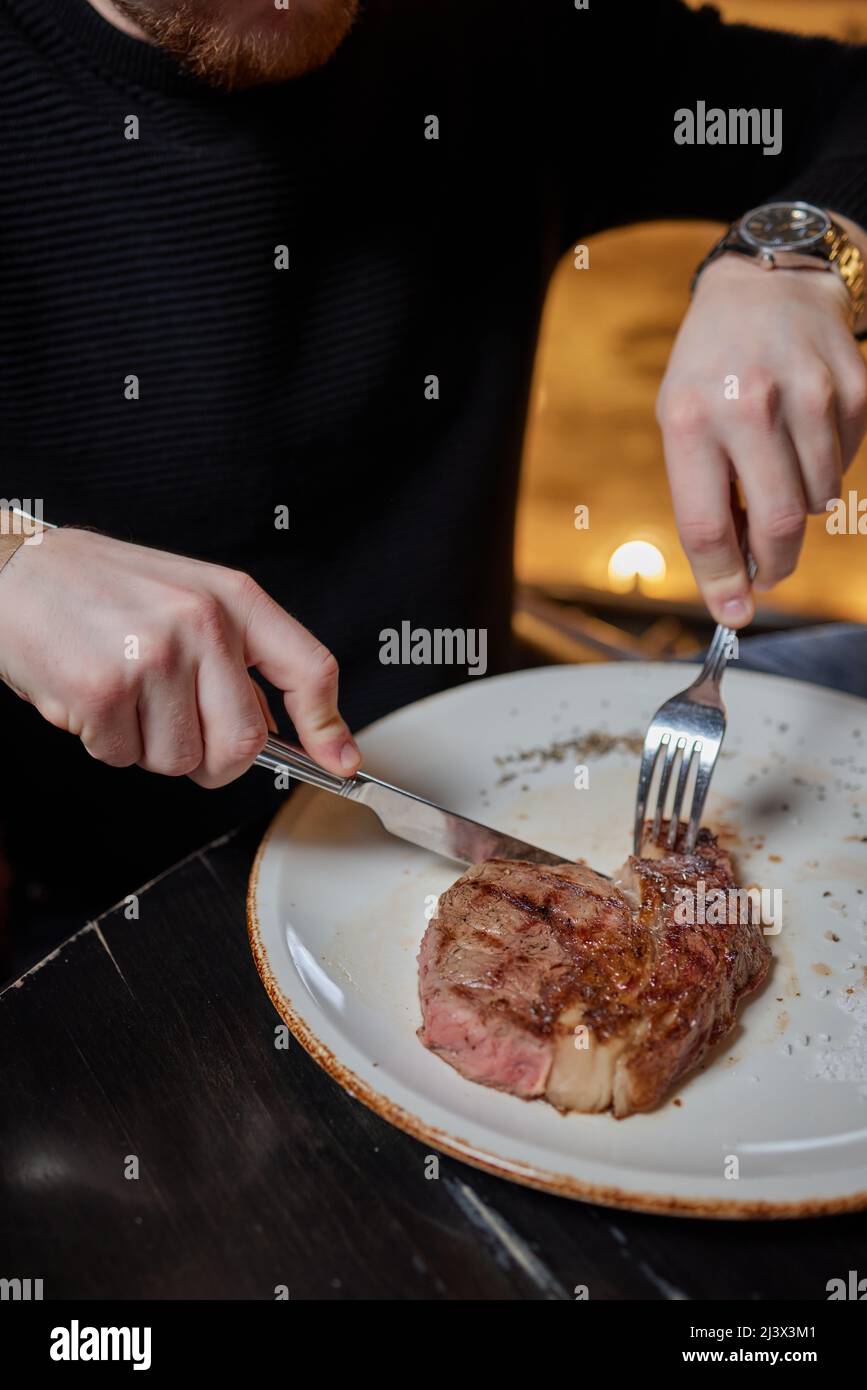 eating stake from plate with fork and knife man hands Stock Photo - Alamy