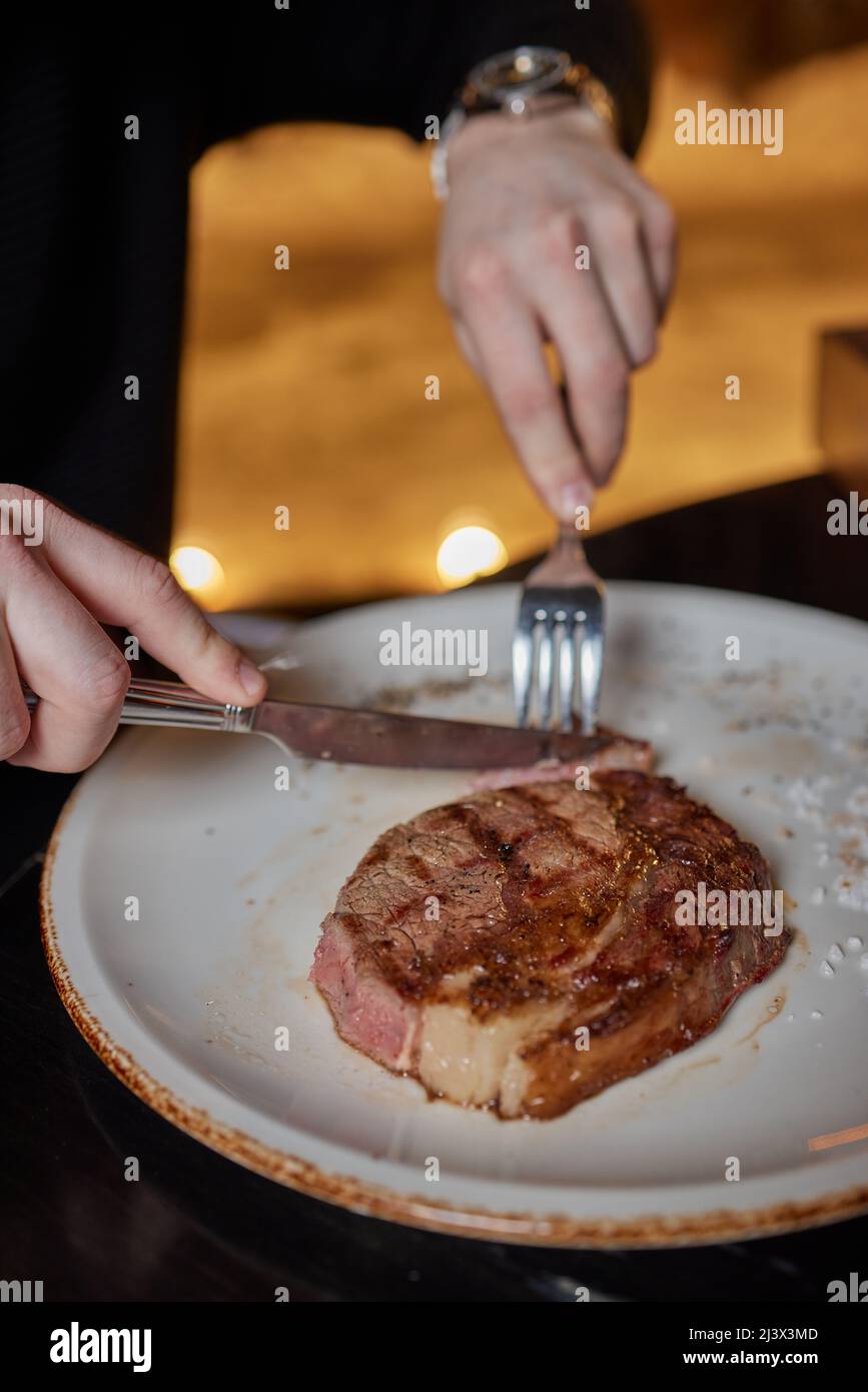 eating stake from plate with fork and knife man hands Stock Photo - Alamy
