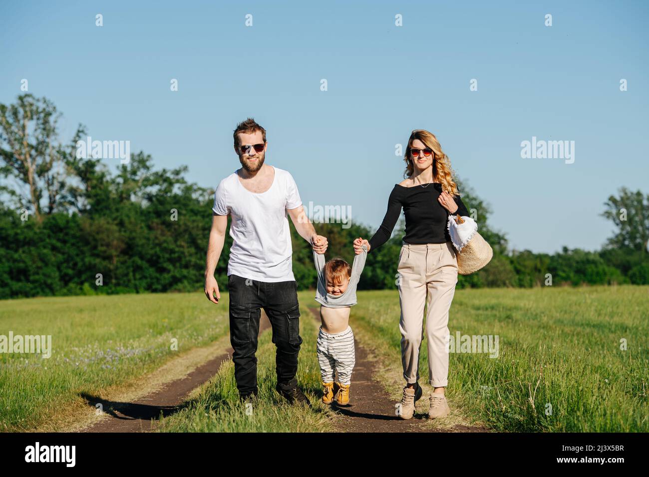 Happy young family walking on a spring grass field in a countryside ...