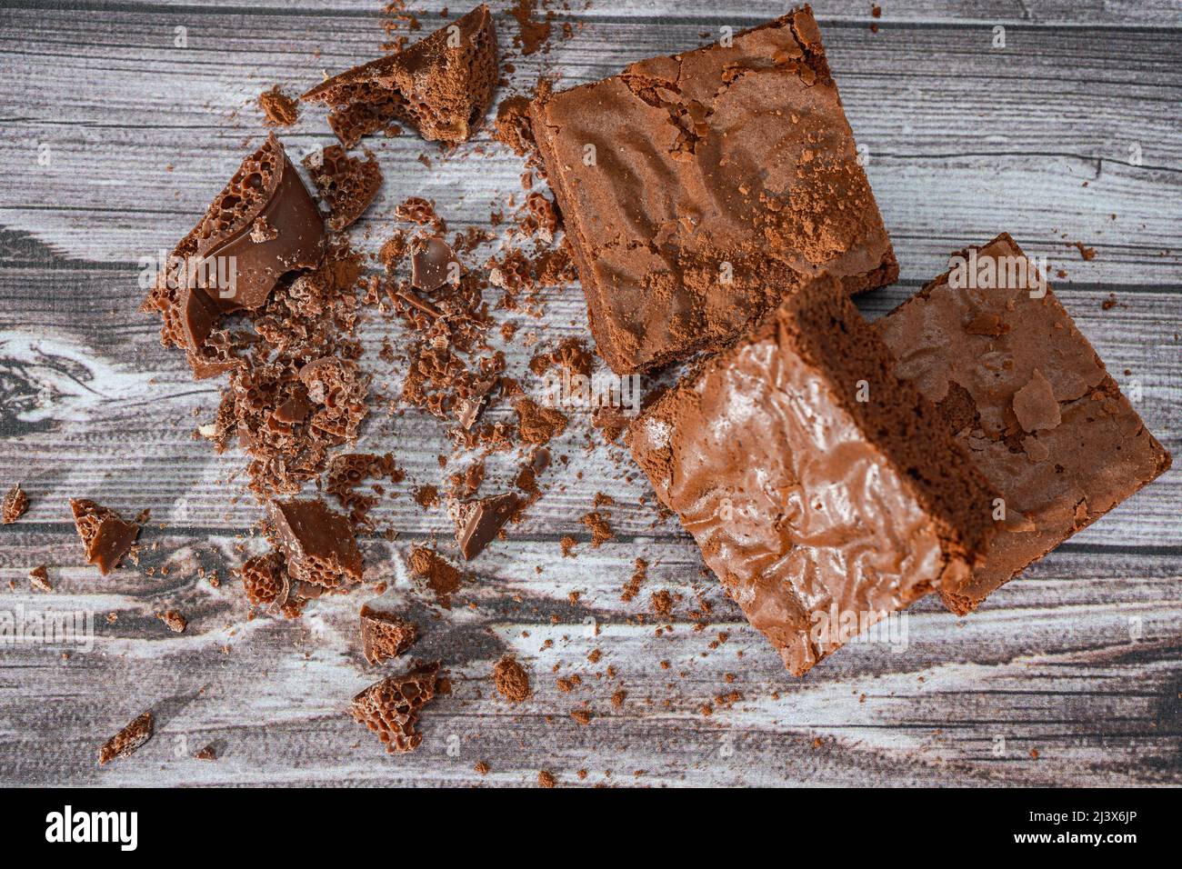 Chocolate brownies on a rustic wooden table with chocolate chips and ...