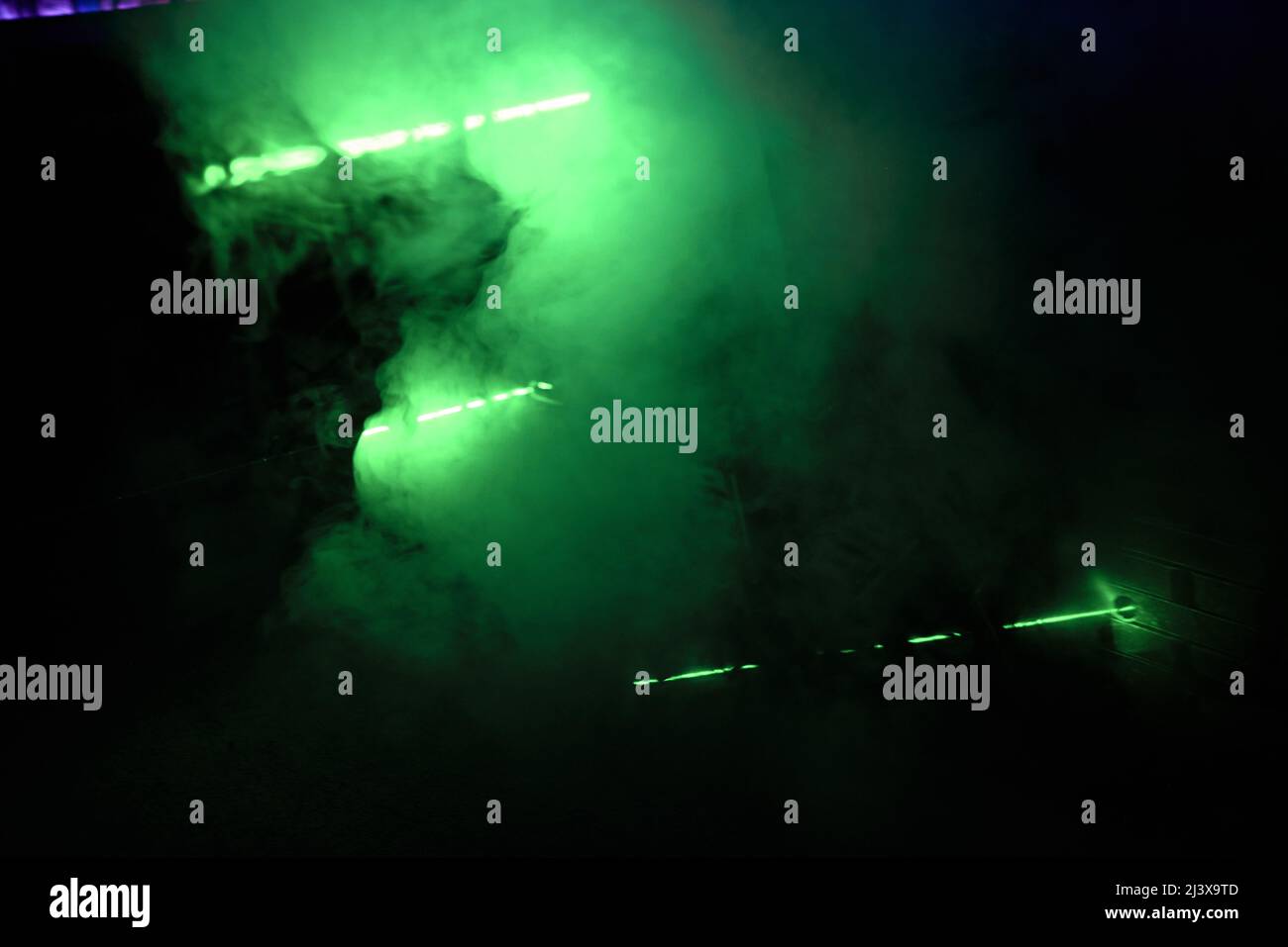Bright green neon laser lights illuminate the darkness creating lines ...