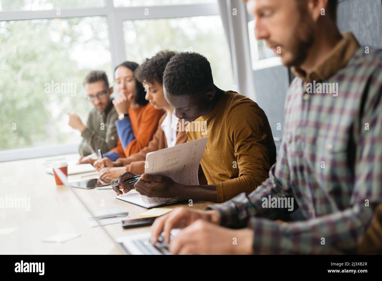 variety of employees sitting at a desk in a coworking center Stock ...
