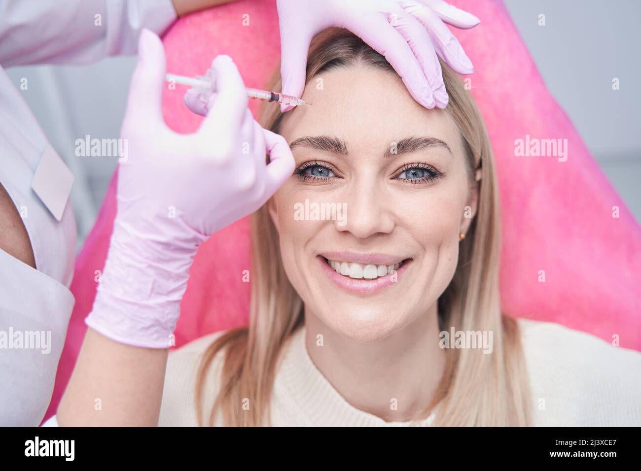 Smiling patient receiving subcutaneous injection into forehead Stock ...