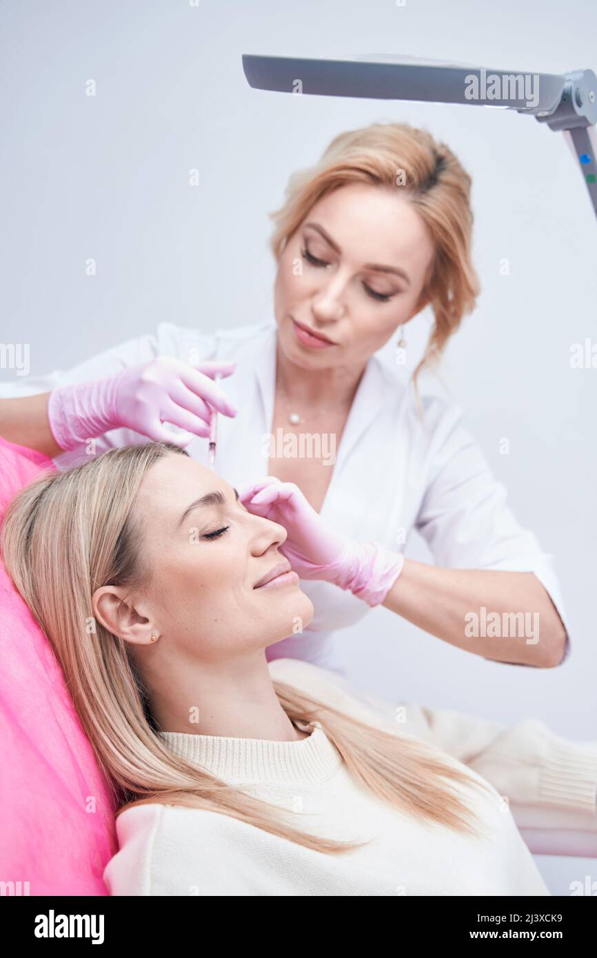 Concentrated dermatologist administering subcutaneous injection to ...