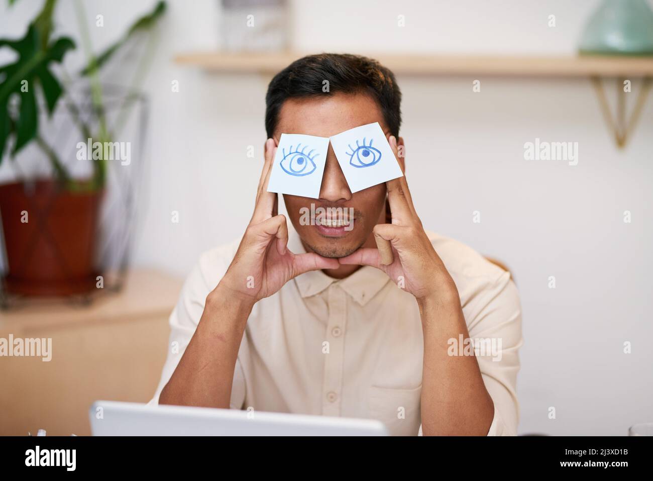 An Asian businessman is stressed at work with eyes drawn on sticky ...