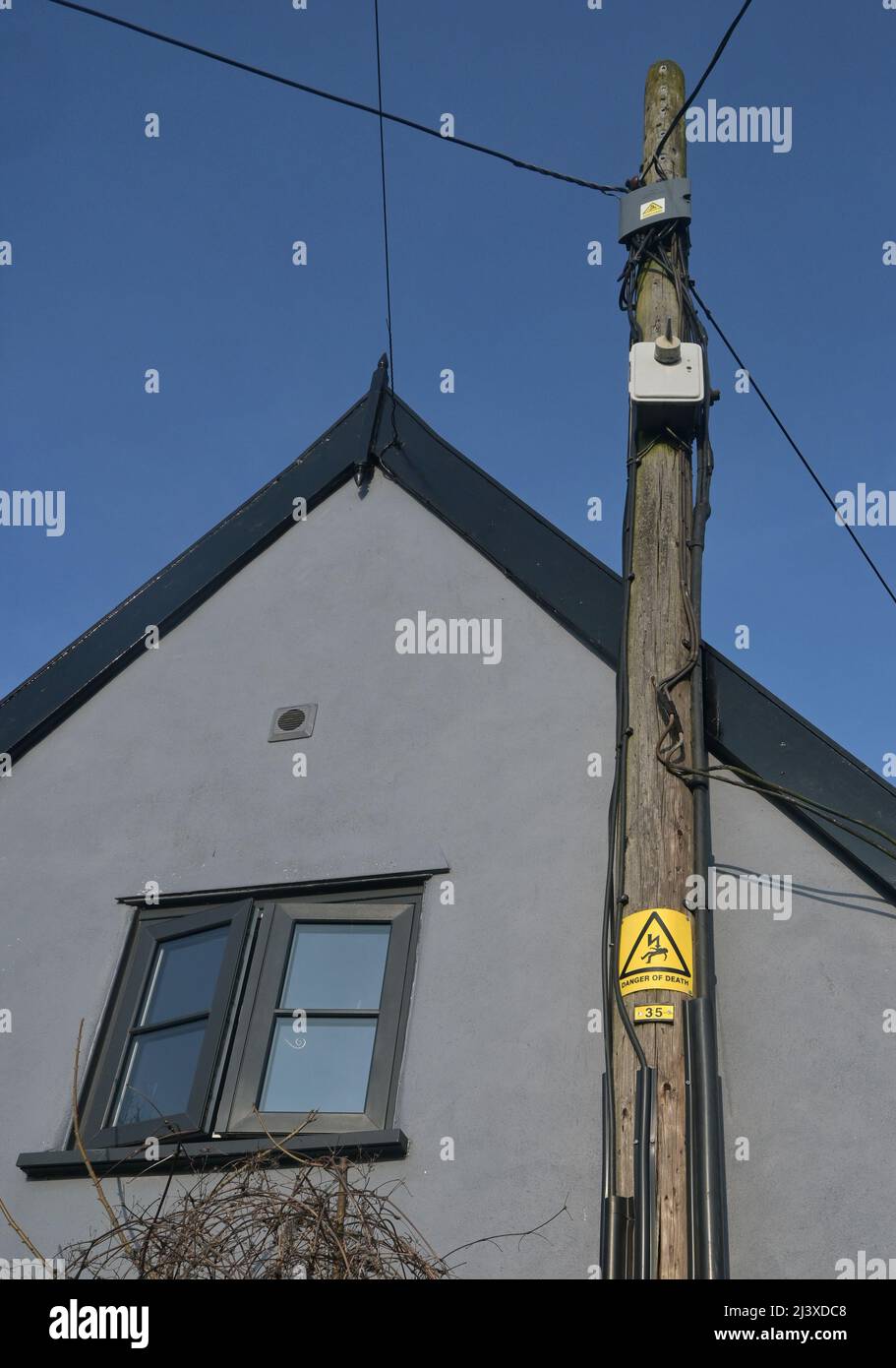 warning sign on pole with electrical cables, england Stock Photo - Alamy