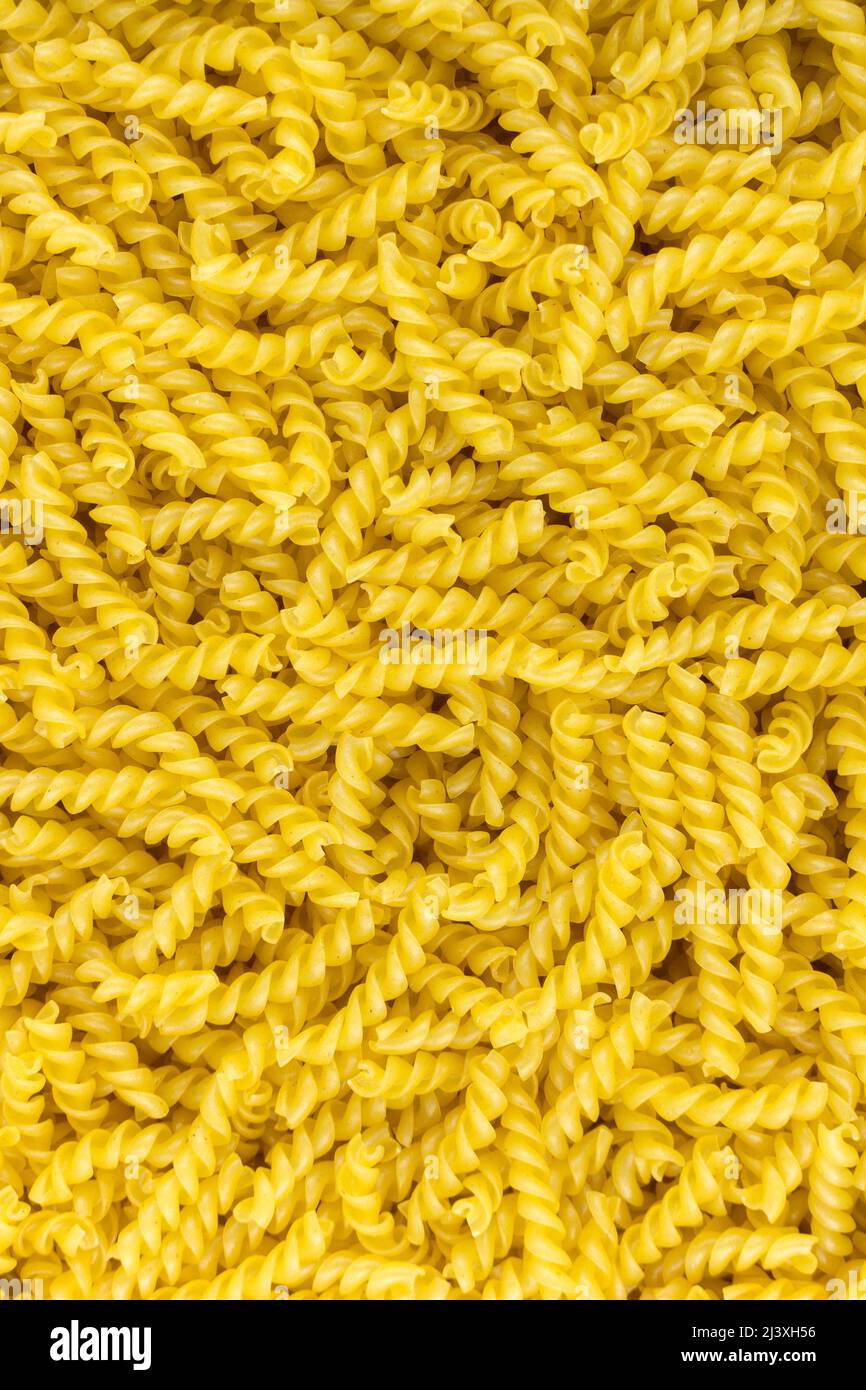 Raw pasta fusilli. spiral shape pasta, yellow background. Top view ...
