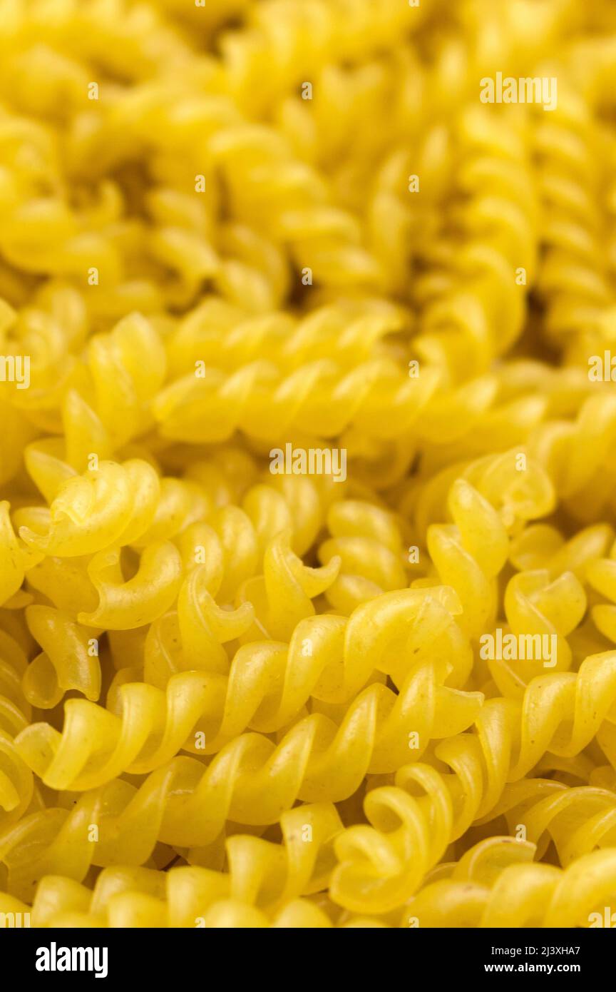 Raw pasta fusilli. spiral shape pasta, yellow background. Top view ...