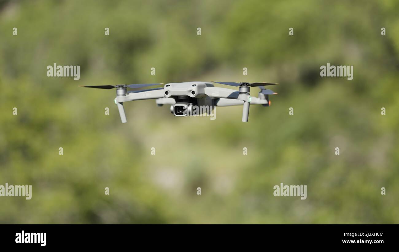 Flying drone in air. Action. Drone flies over green trees. New model of drone in air shoots ...