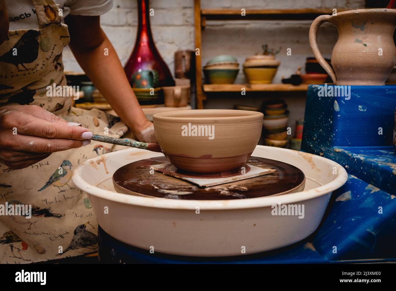 Potter working on potters wheel with clay. Process of making ceramic tableware in pottery ...