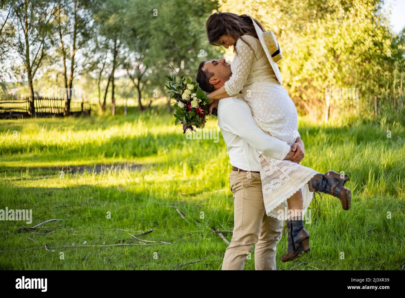 Stylish happy bride, groom hold picked up in hands and dancing. The ...