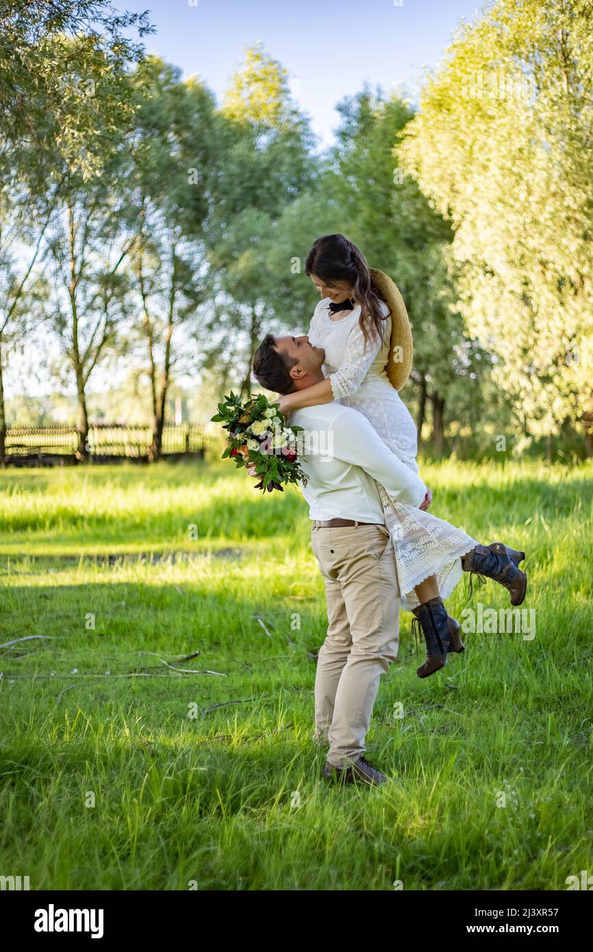 Stylish happy bride, groom hold picked up in hands and dancing. The ...