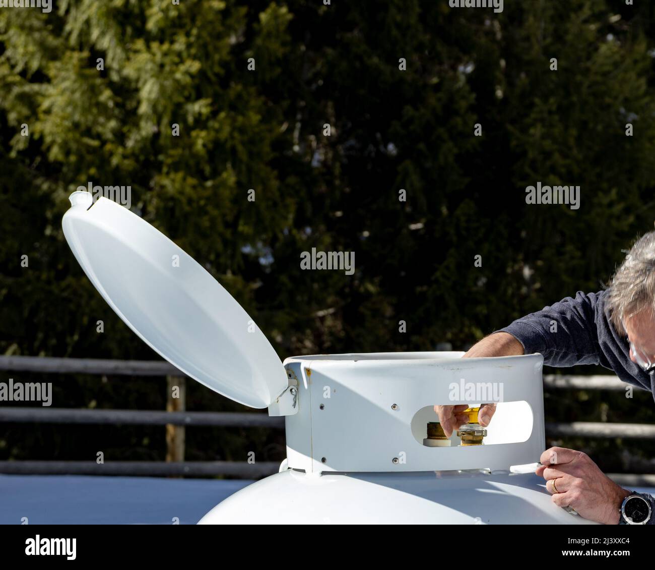 Large propane tank with man turning on off valve Stock Photo - Alamy