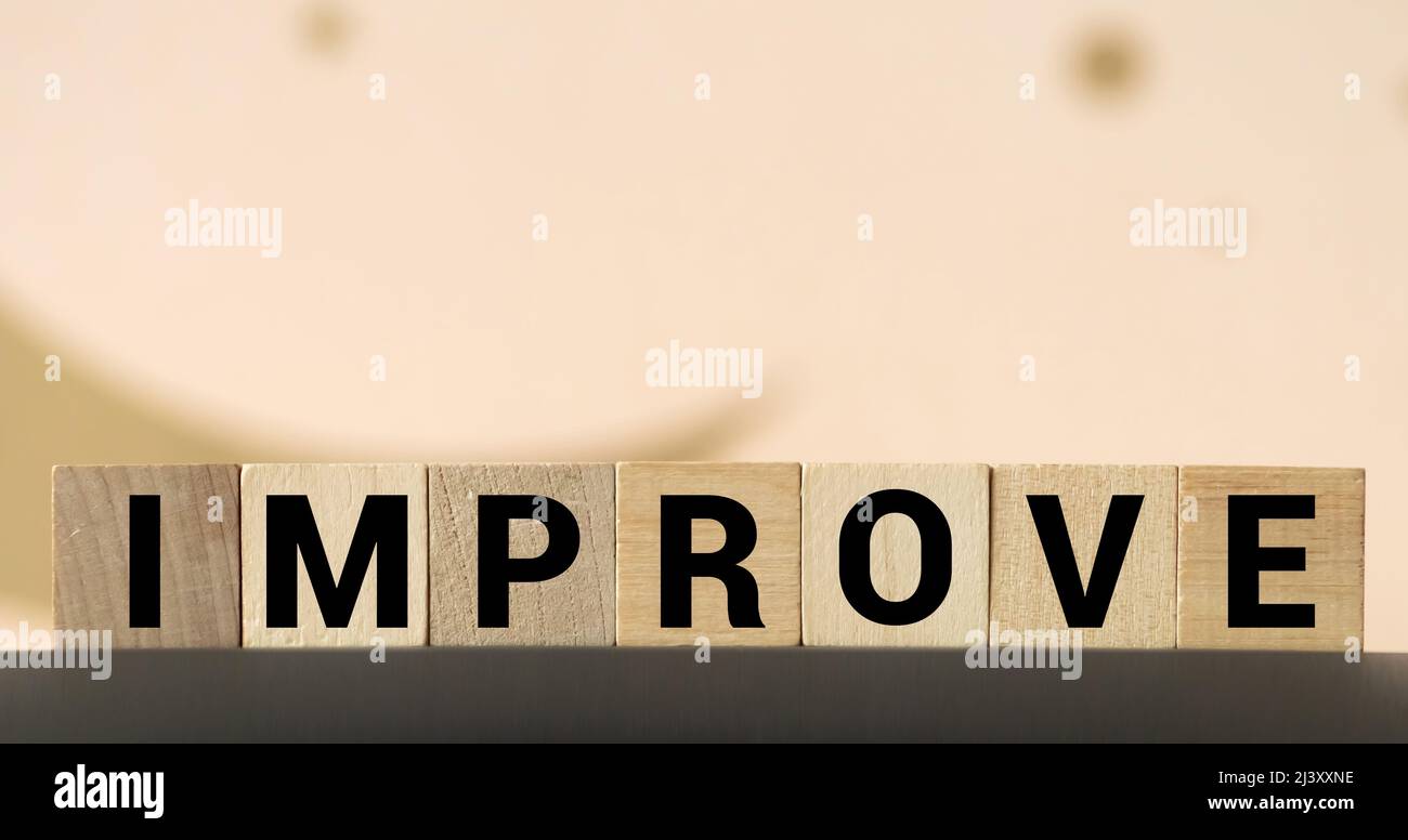 Wooden cubes with letters on a white table. The word is IMPROVE. White ...
