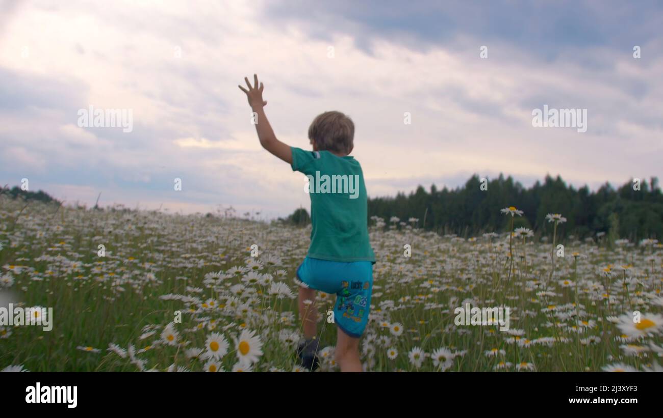 Rear view of happy kid running in green field. Creative. Kid running ...